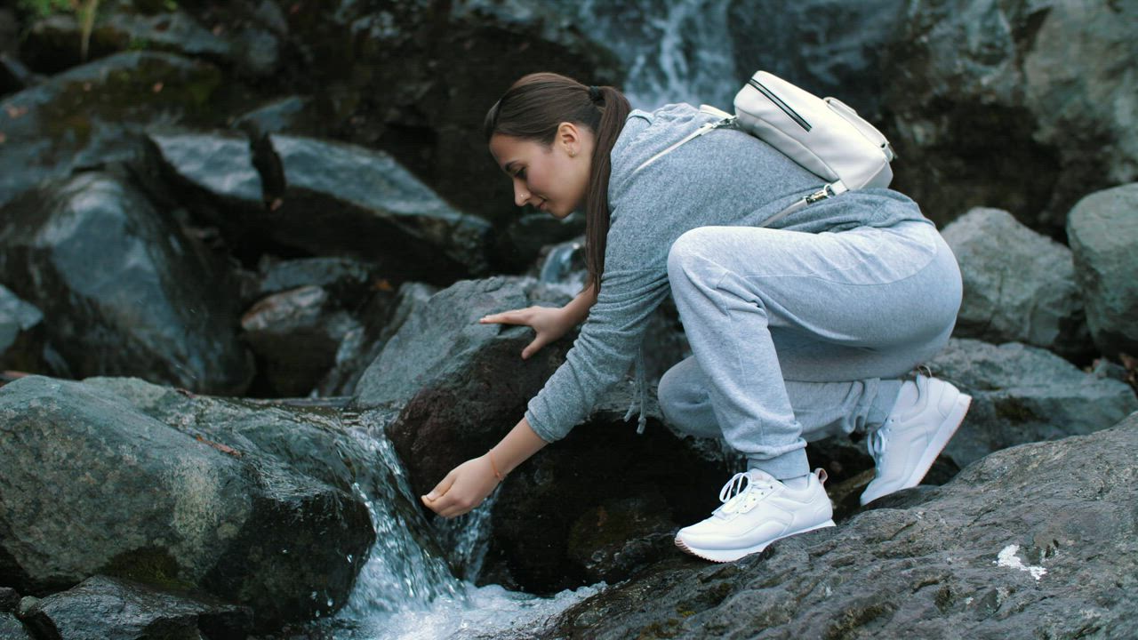 Woman drinks water from the waterfall - Free Stock Video