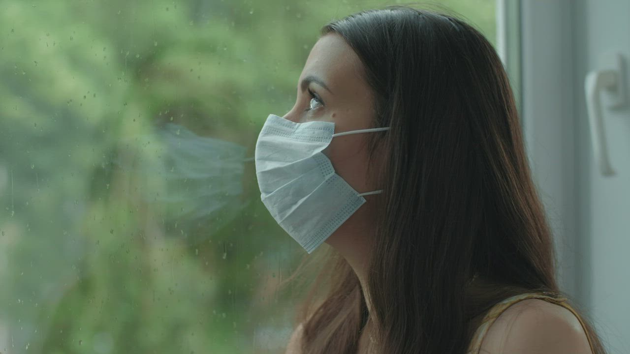 Woman with mask looking out the window - Free Stock Video