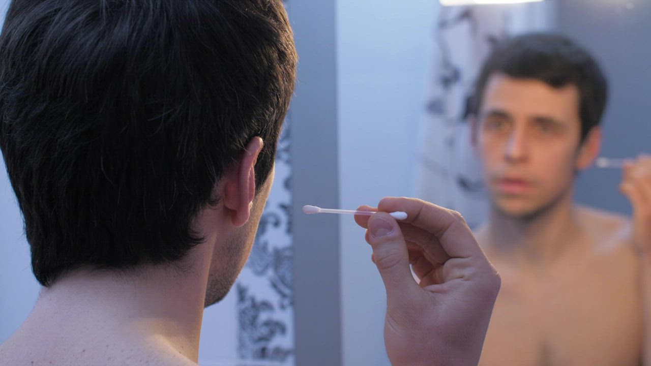 Man cleaning his ears in the bathroom mirror - Free Stock Video