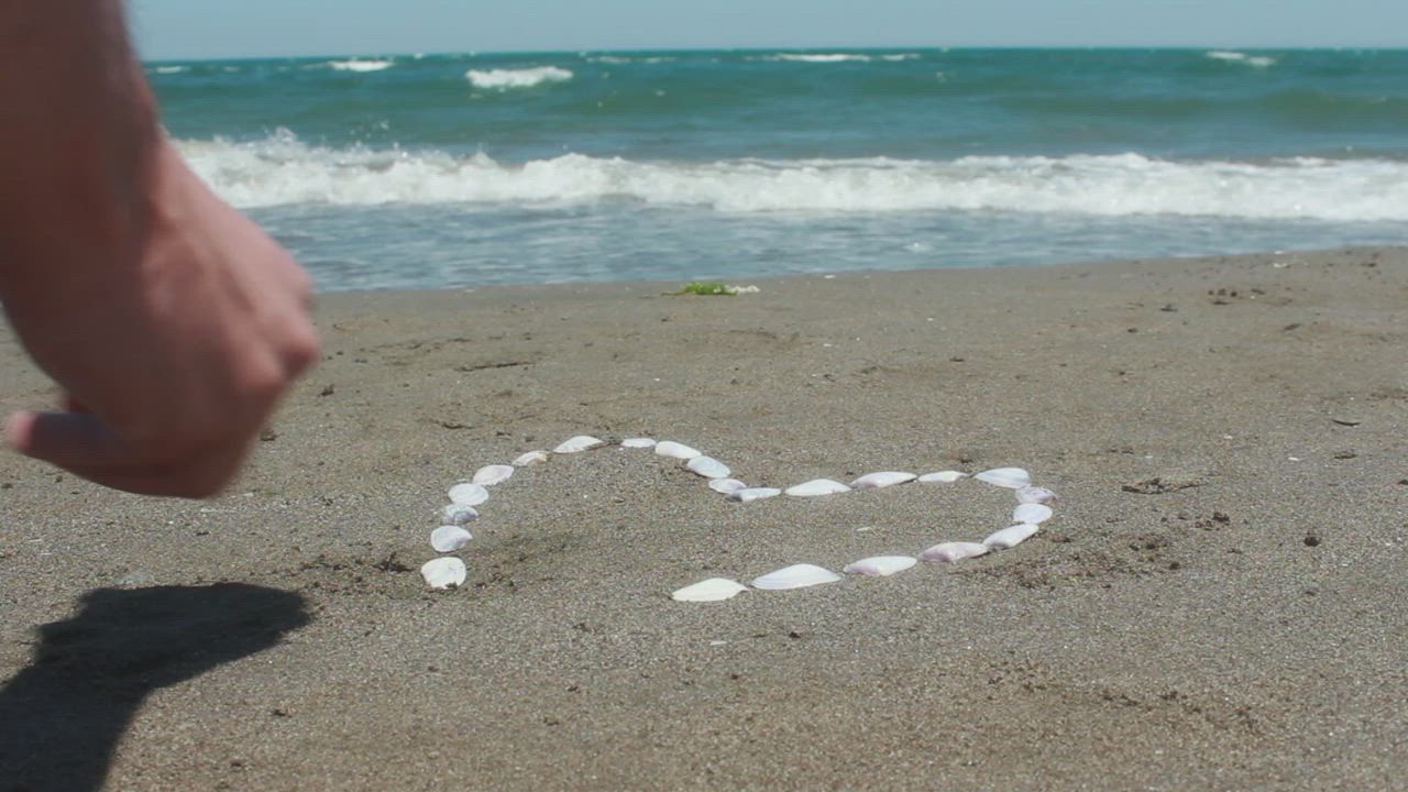 Drawing a heart on the beach using oysters - Free Stock Video