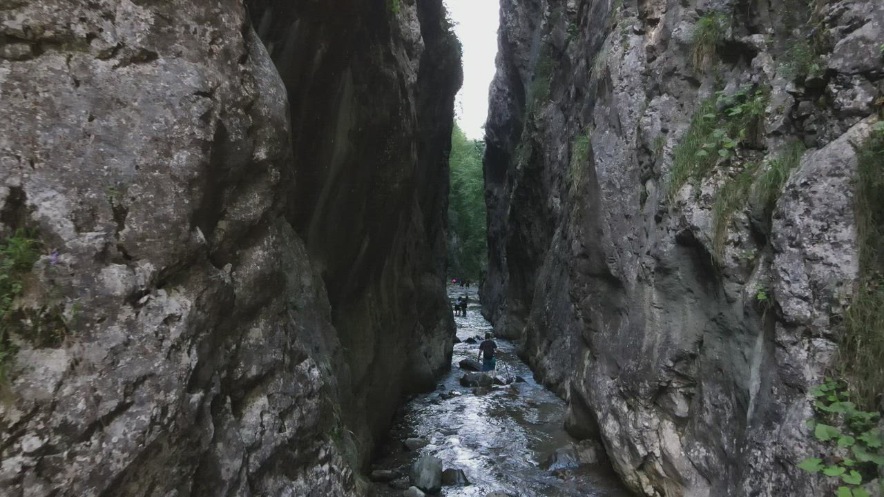 Explorers crossing a river between two mountains - Free Stock Video