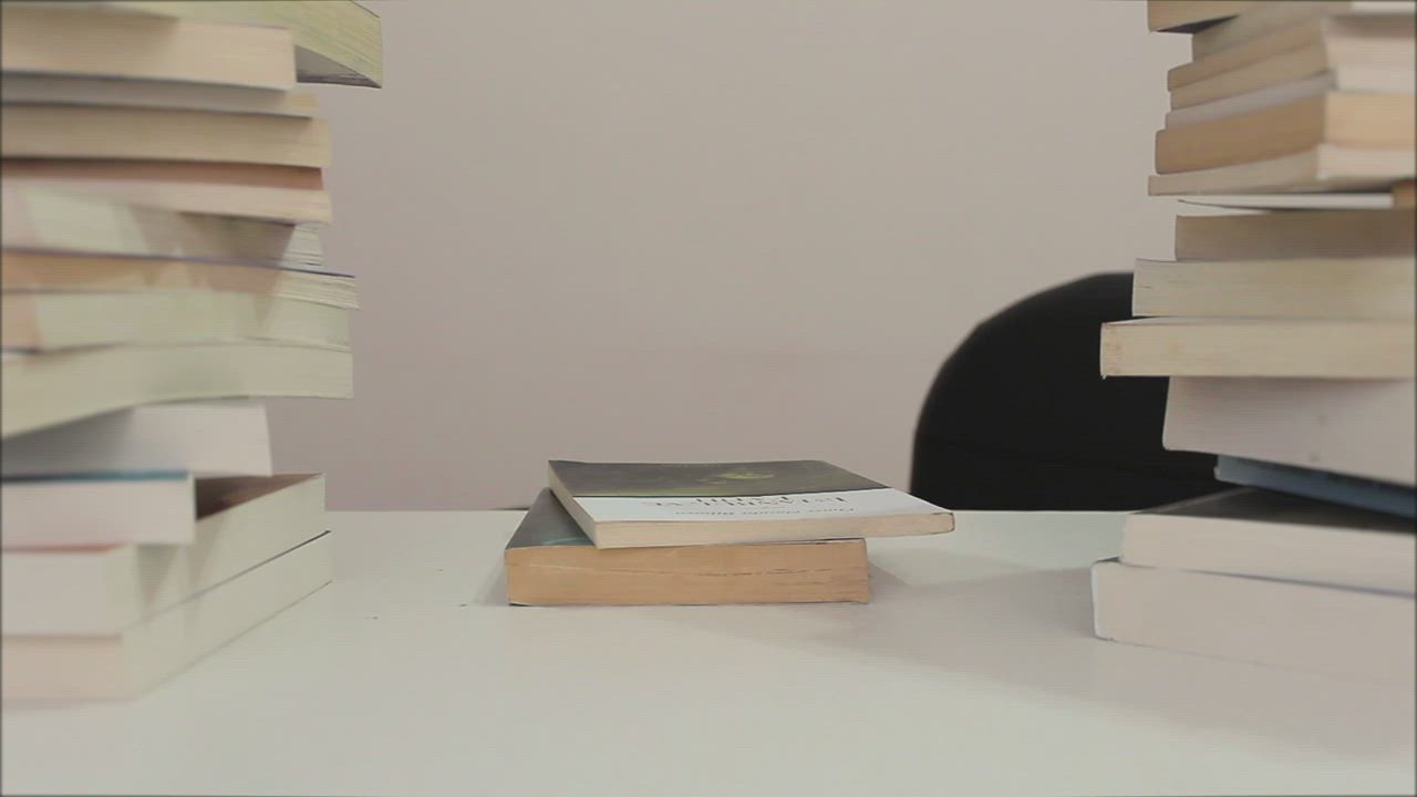 Person sits down to read surrounded by many books - Free Stock Video