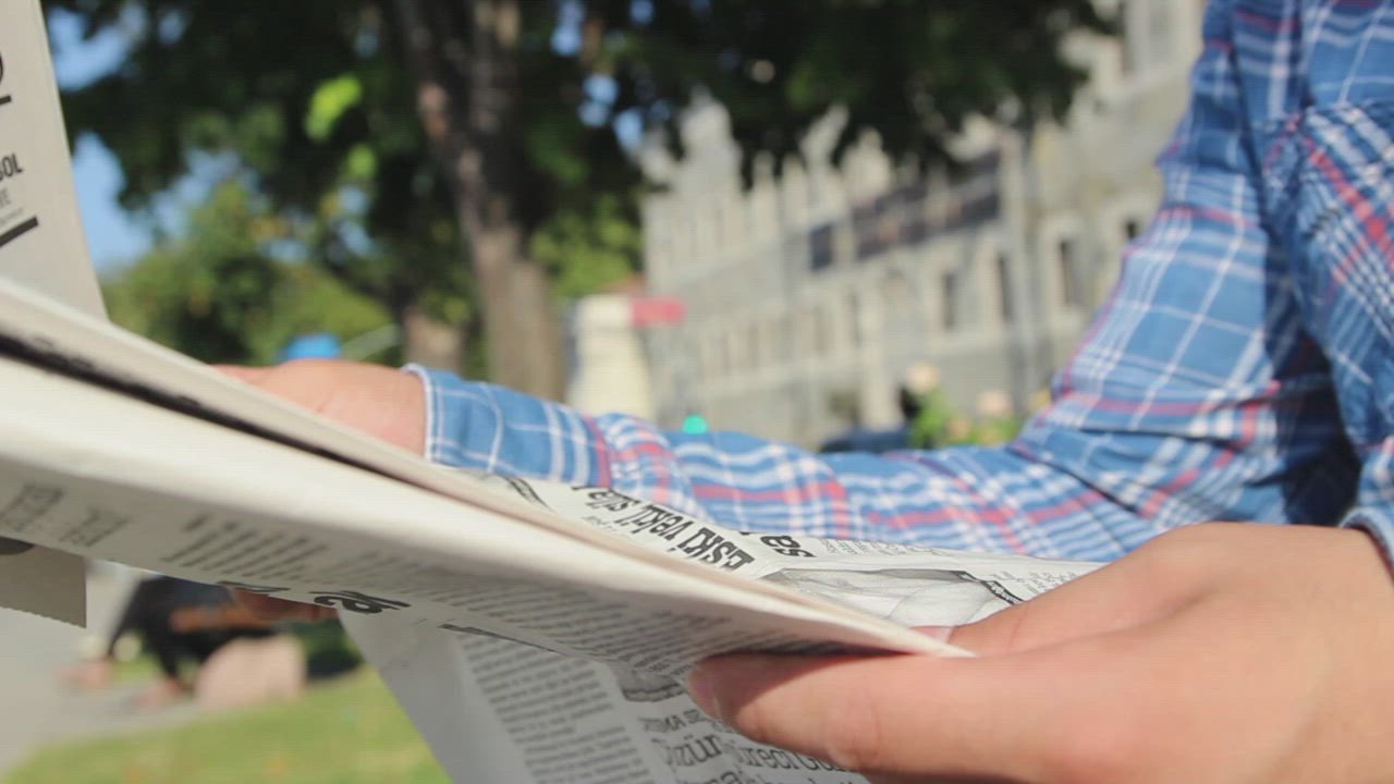 Person reading the newspaper in a park outdoors - Free Stock Video
