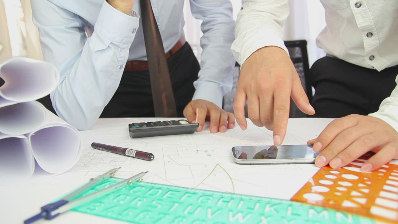 Two architects discussing a project on a desk - Free Stock Video