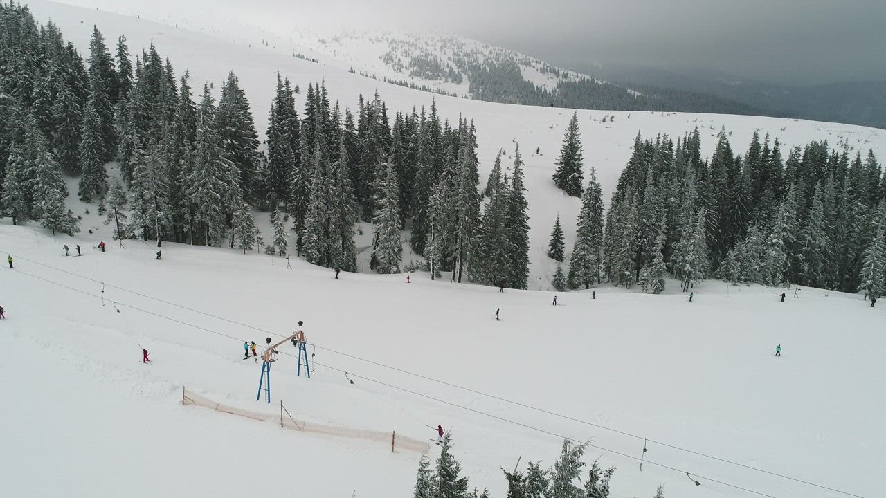 Flying over mountains slope with skiers - Free Stock Video