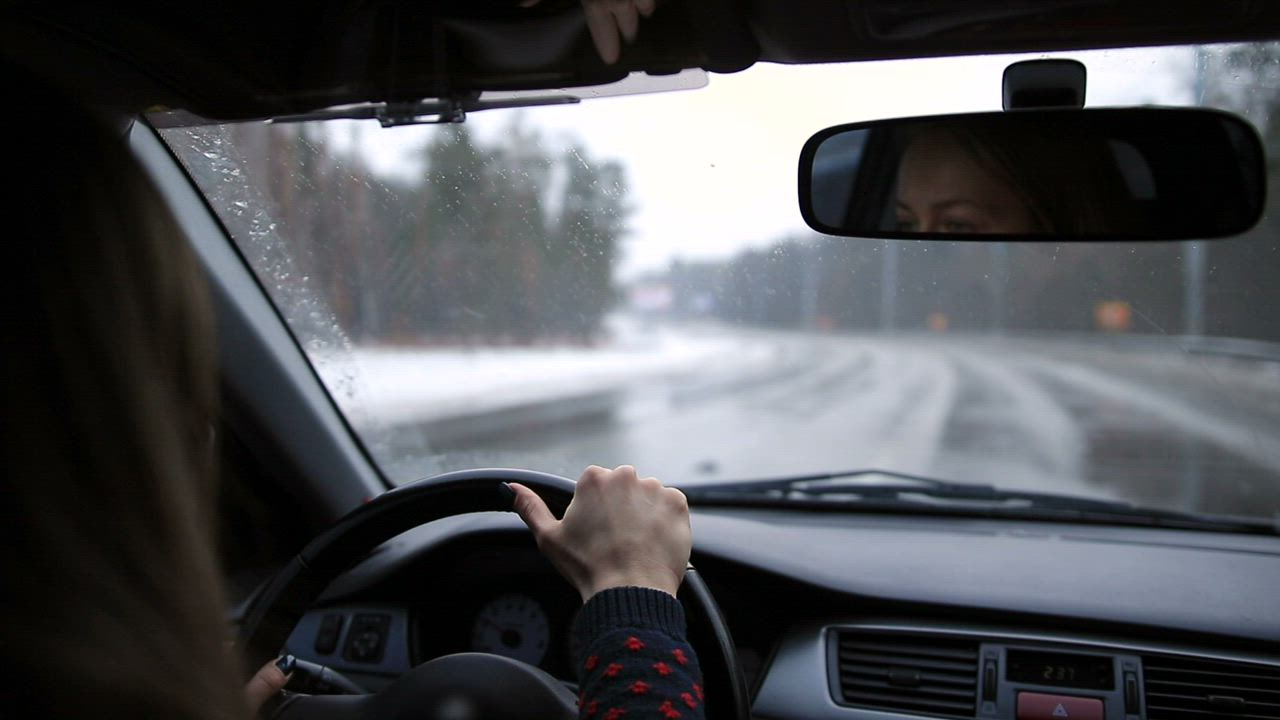 Woman driving down a lonely road on a snowy day - Free Stock Video