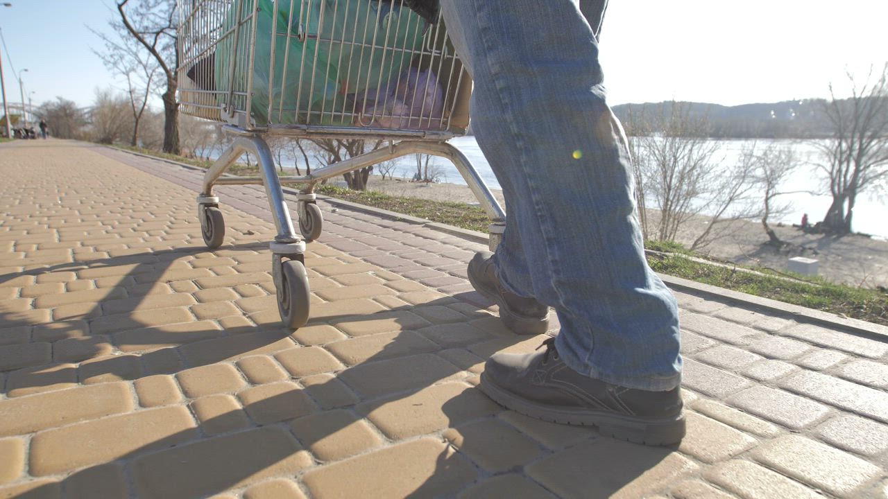 A tramp walking in the sun with a metal cart - Free Stock Video