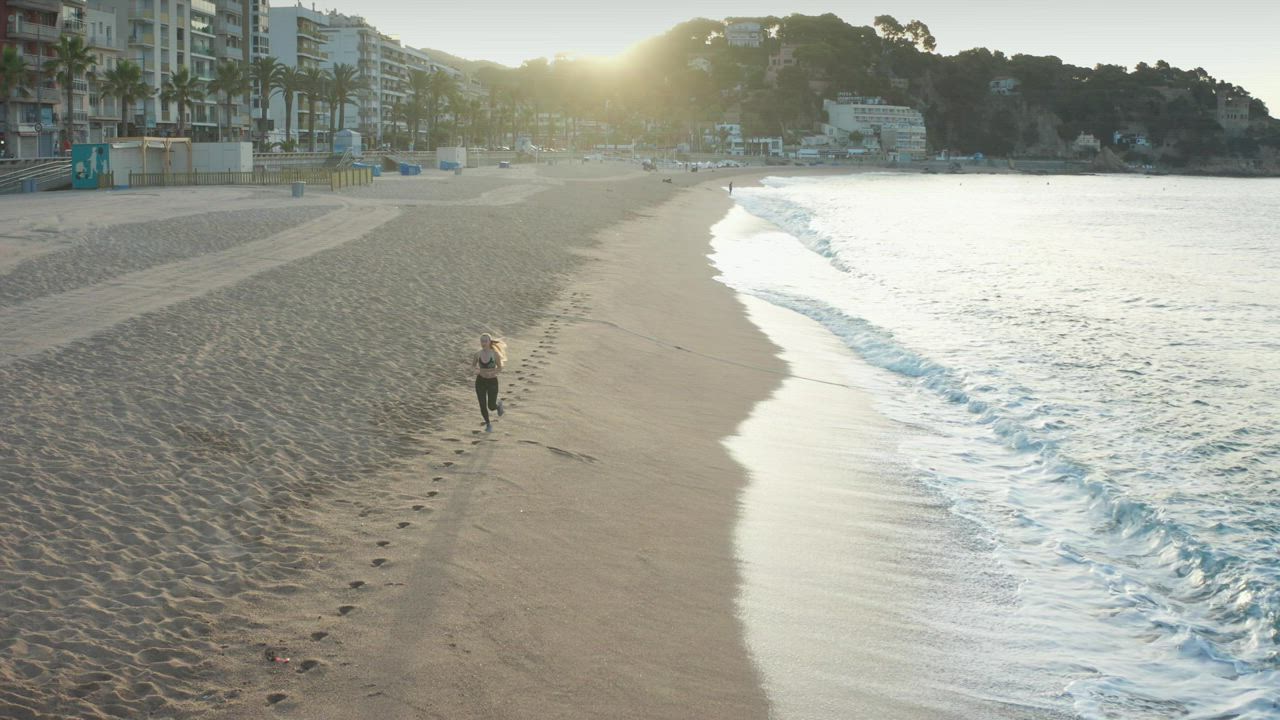 Woman running on the seashore, aerial shot - Free Stock Video