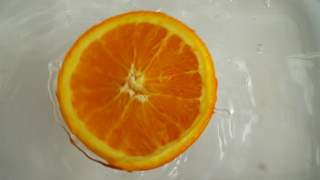 Half an orange floating and spinning in water - Free Stock Video