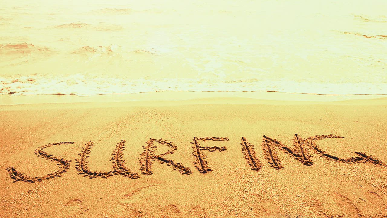 "Surfing" written in the sand on a sunny beach - Free Stock Video