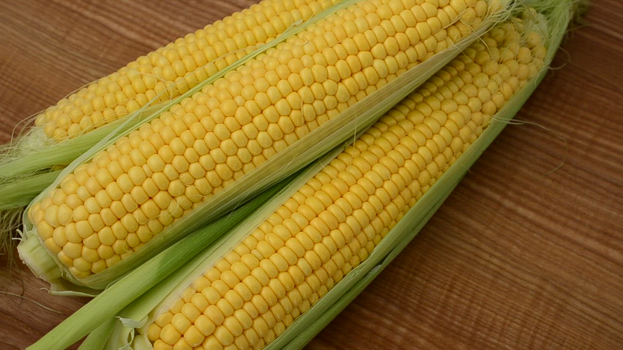 Ears of corn, turning on a wooden surface - Free Stock Video
