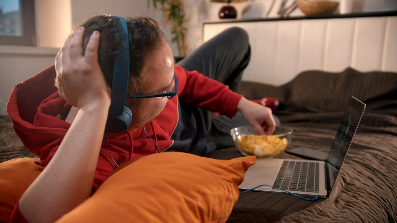 Young man watching videos and eating snacks - Free Stock Video