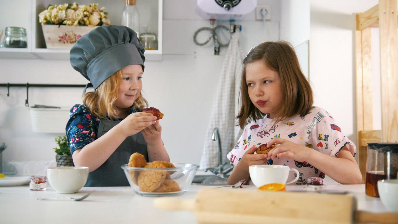 Two girls in a kitchen eating fresh cookies - Free Stock Video