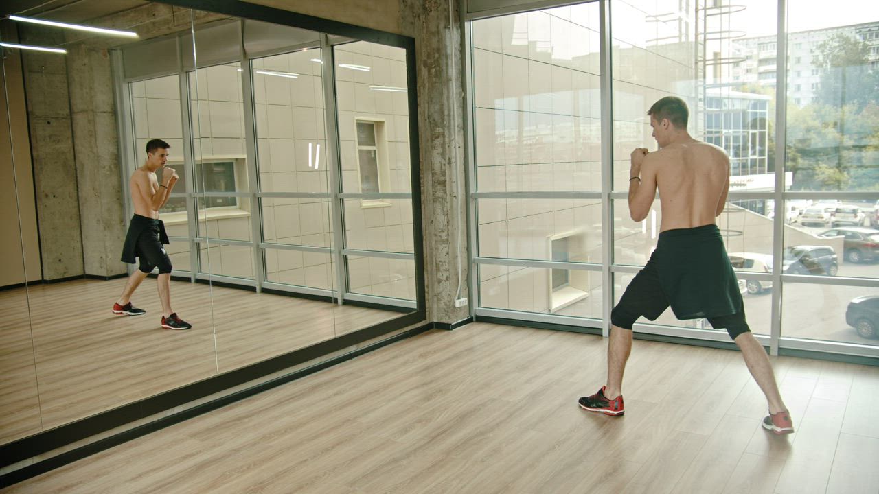 Young man practicing martial arts in a mirror - Free Stock Video
