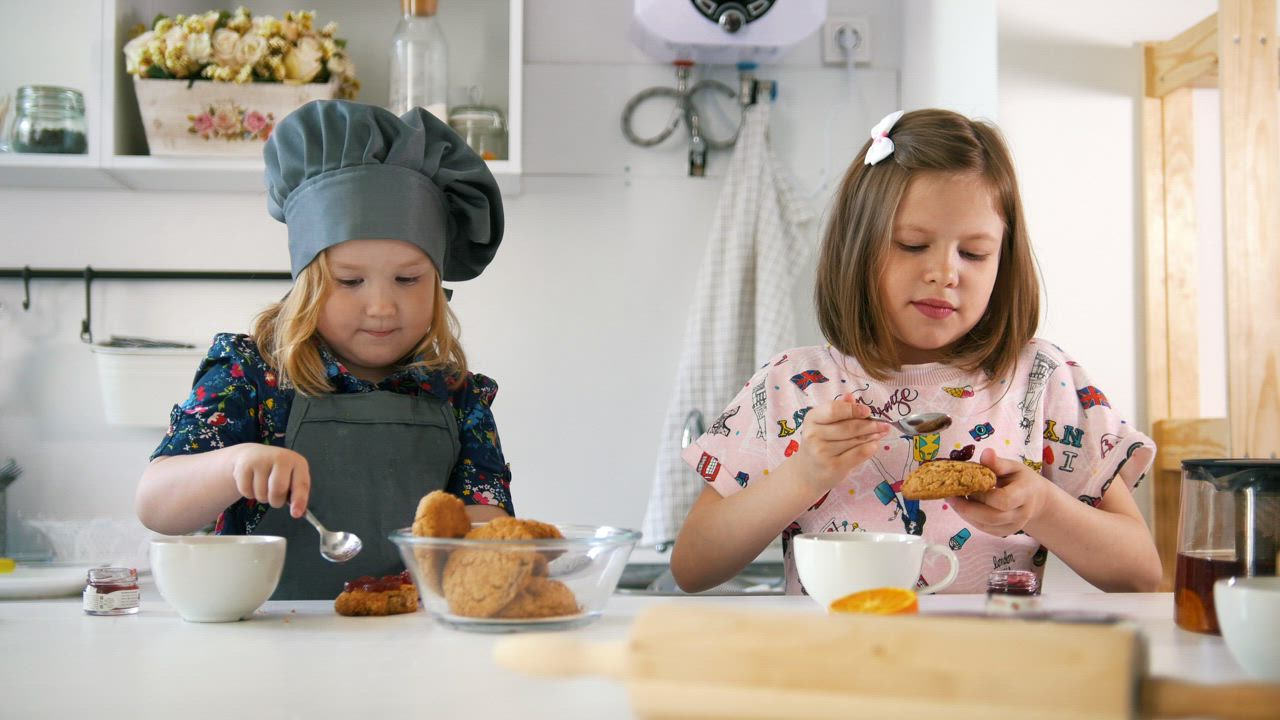 Two girls in the kitchen eating cookies with jam - Free Stock Video