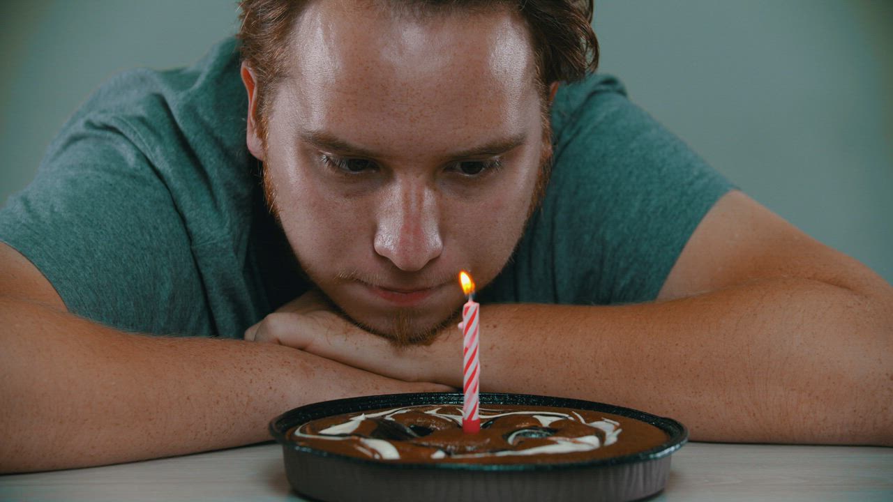 Crestfallen man blowing out the candle on a cake - Free Stock Video
