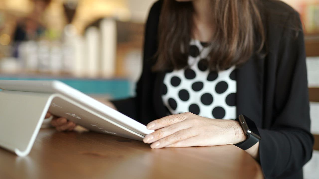 Woman syncing her smart watch with her tablet - Free Stock Video