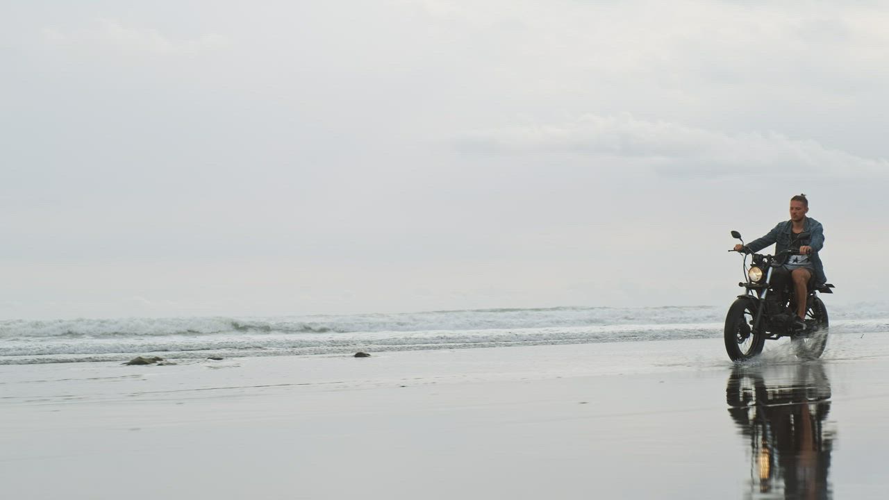 Wanderlust biker having a ride on the beach - Free Stock Video