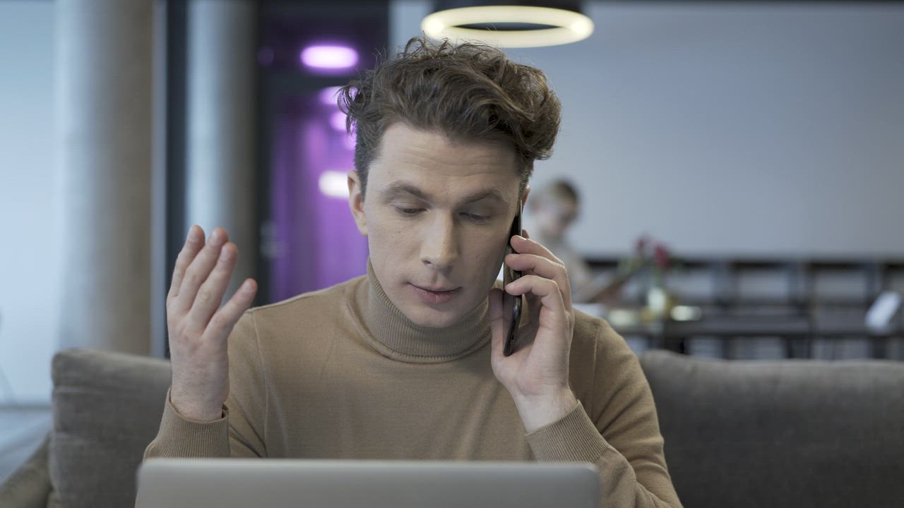 Man talking on the phone while working on the computer - Free Stock Video