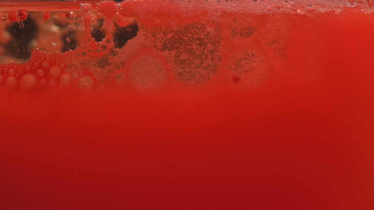 Close-up view of a bubbling red liquid - Free Stock Video