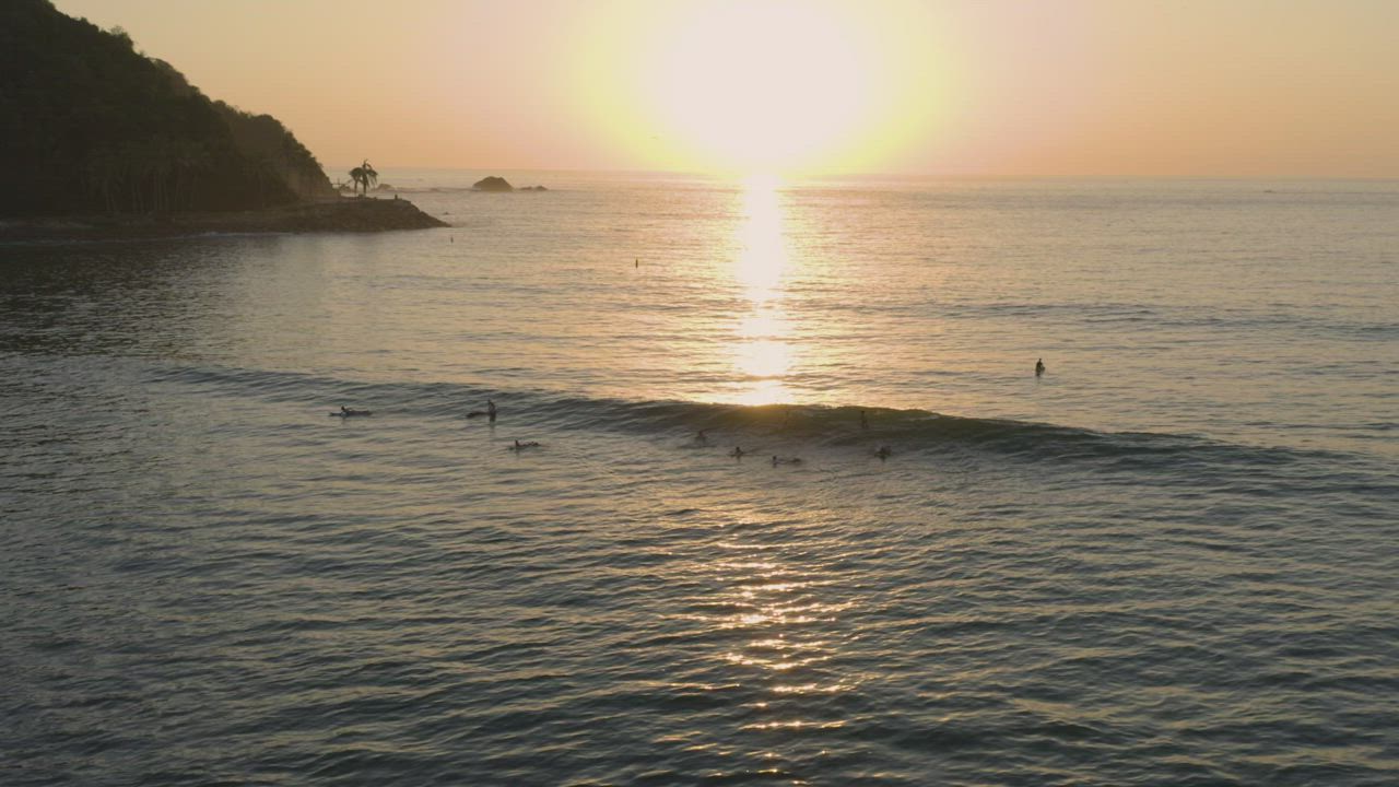 Surfing waves near a shoreline at sunset - Free Stock Video