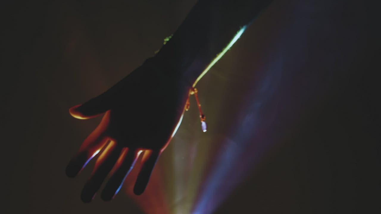 Hand of a person in the dark through colored lights - Free Stock Video