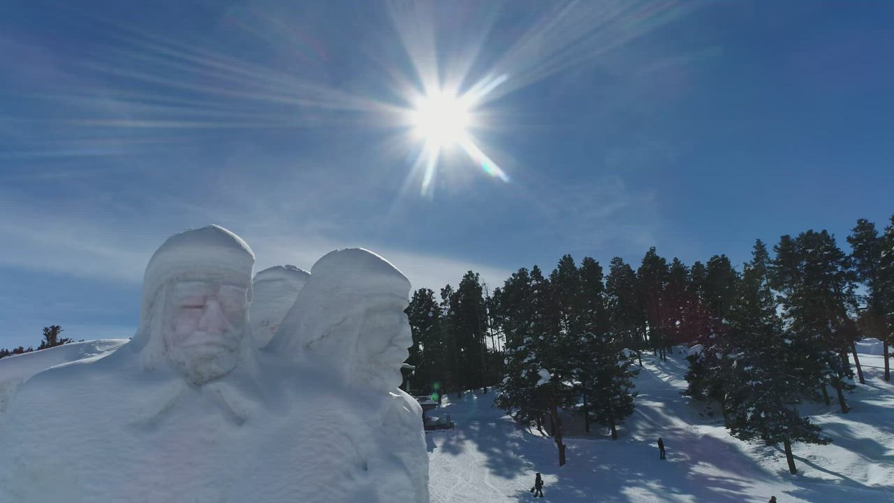 Snow statues on a snowy mountain range with skiers - Free Stock Video