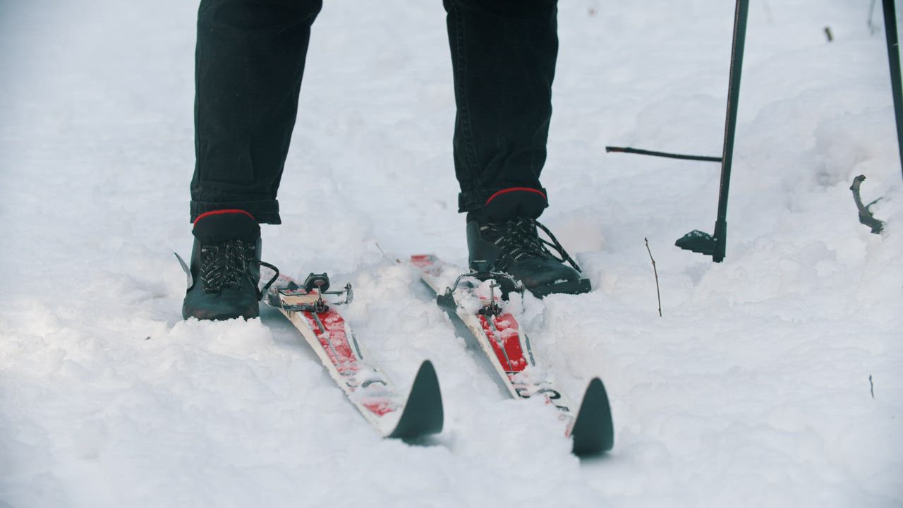 Putting feet up on a pair of skis in the snow - Free Stock Video