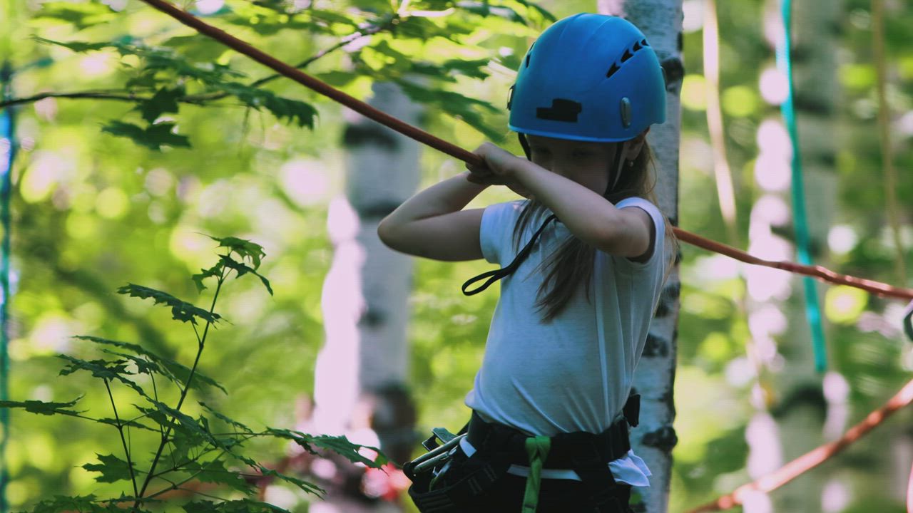 Girl crossing between trees with ropes and a harness - Free Stock Video