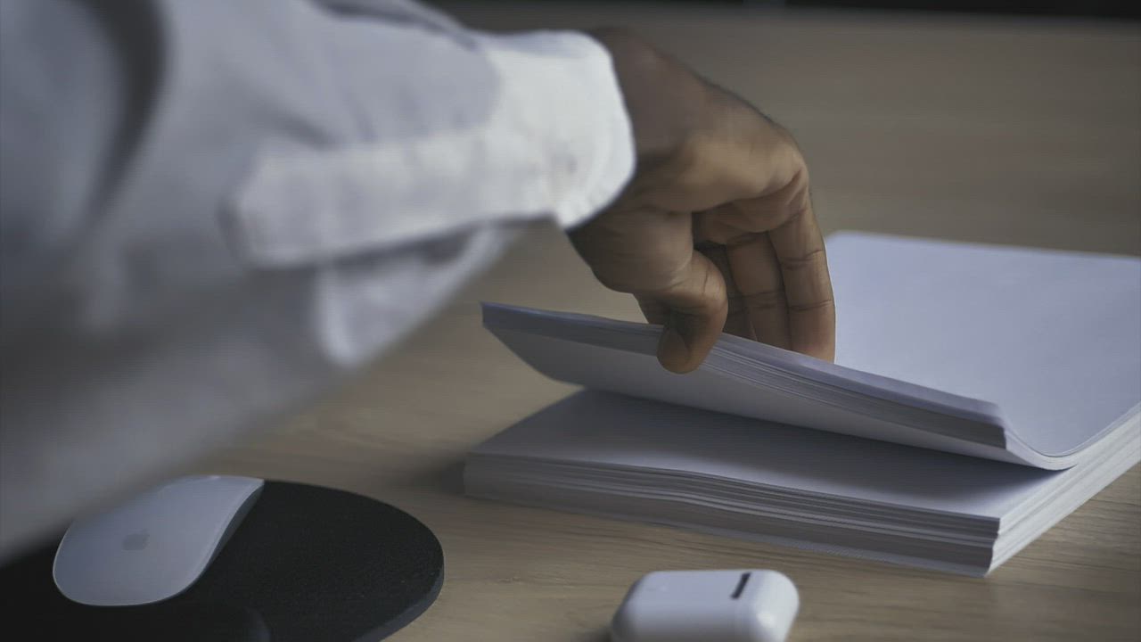 Man in an office taking a white sheet of paper - Free Stock Video