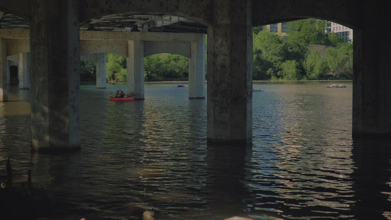 People rowing in a river under a large bridge - Free Stock Video