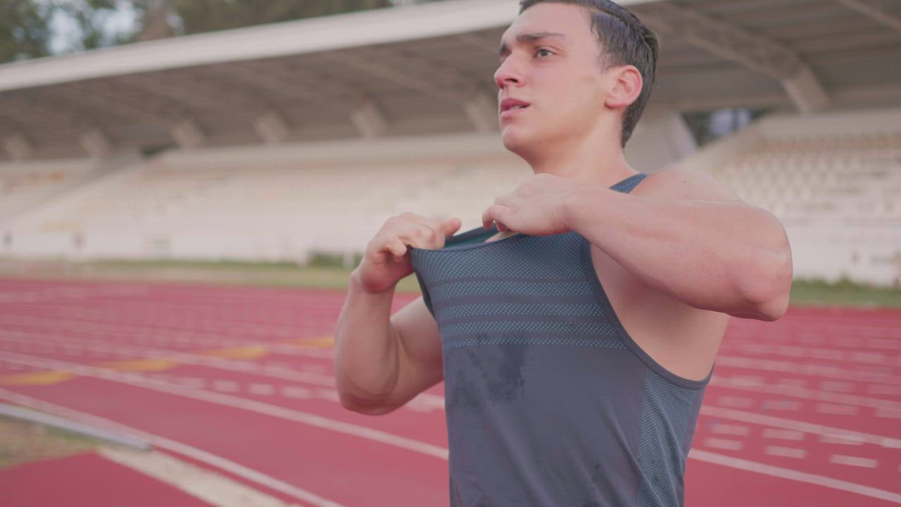 Athletic man takes off his shirt after exercise - Free Stock Video