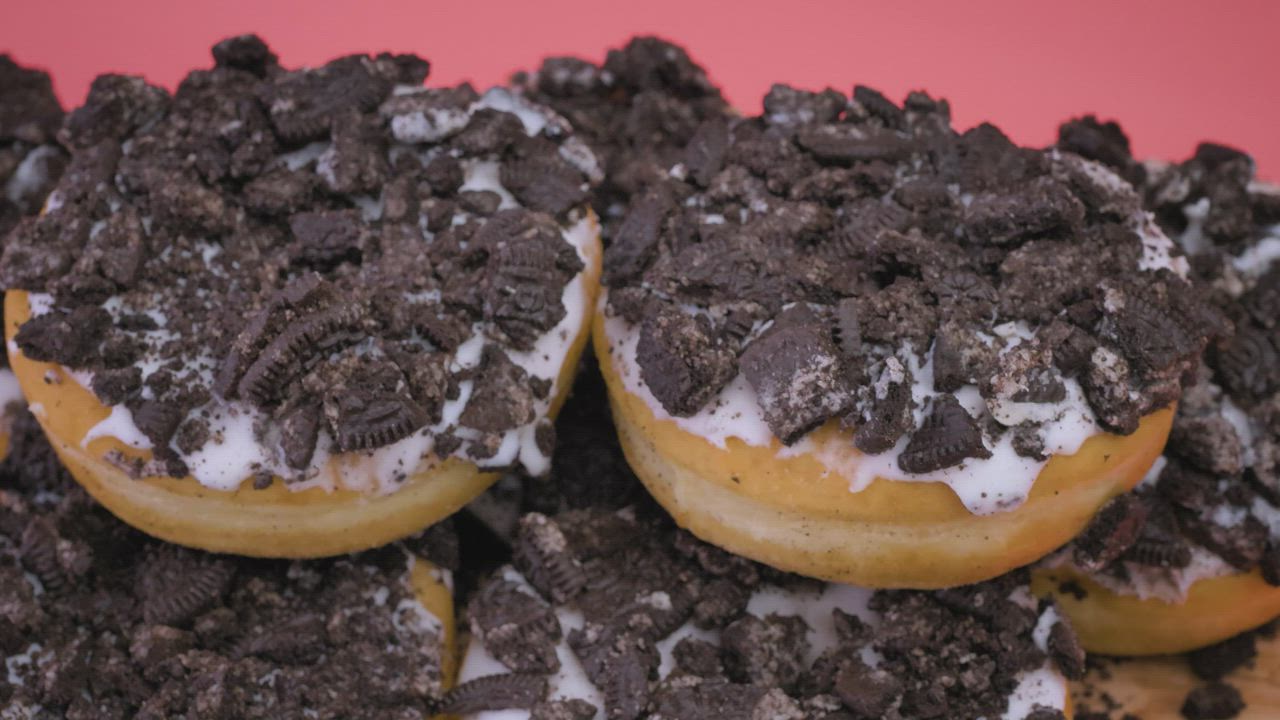 Stacking a tower of donuts with cookie chunks - Free Stock Video