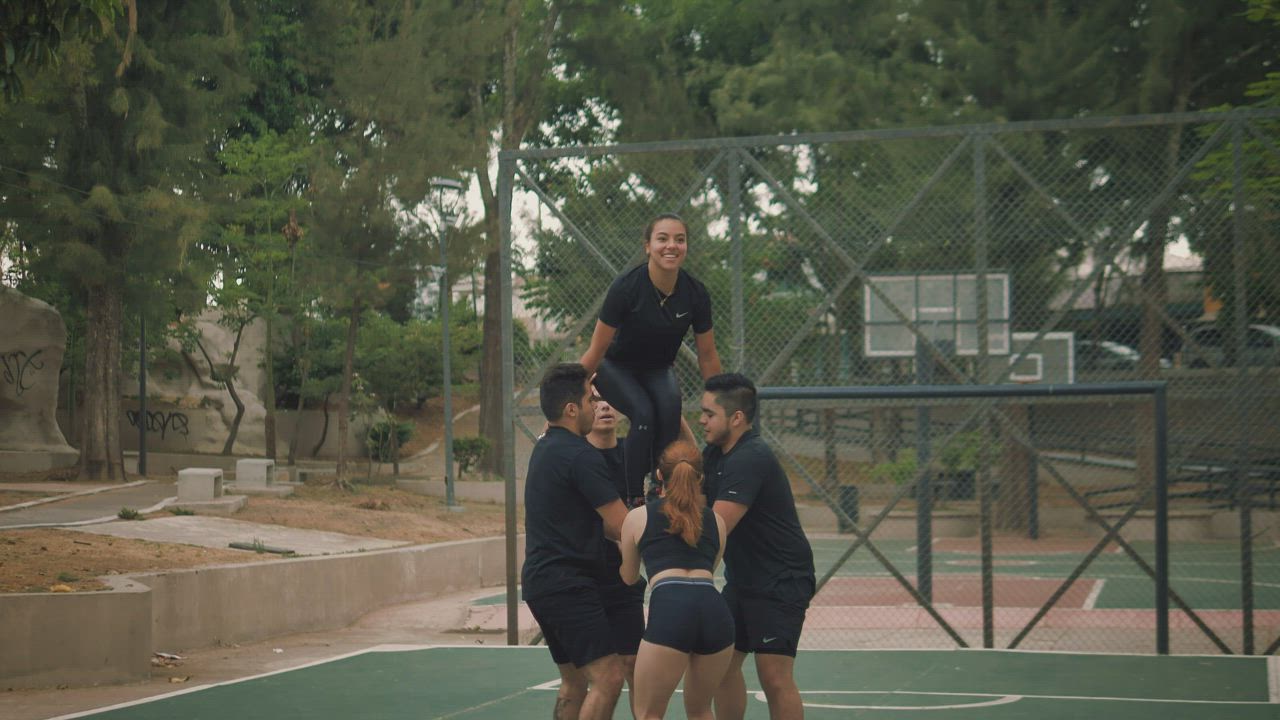 Cheerleaders throwing a girl into the air at a workout - Free Stock Video