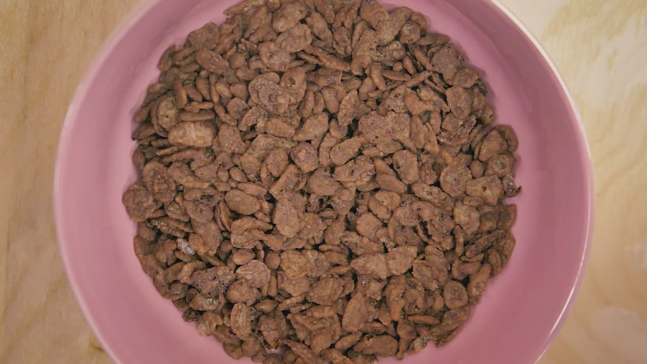 Adding nutritious cereal to a bowl of milk - Free Stock Video
