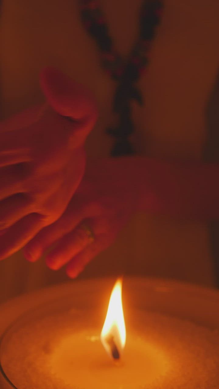 Woman passing her hands near the flame of a candle - Free Stock Video
