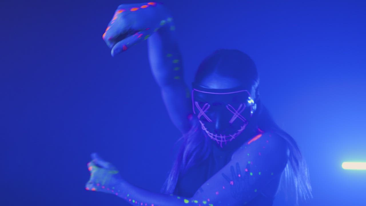 Urban girl dancing with a neon mask under a party light - Free Stock Video