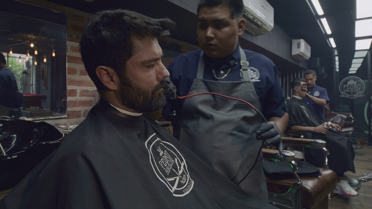Barber working in his barbershop with a client - Free Stock Video