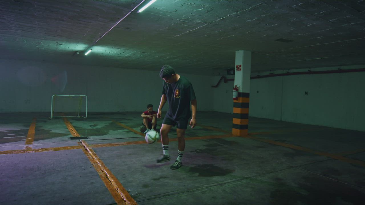 Skilled freestyler juggling the ball in a parking lot - Free Stock Video