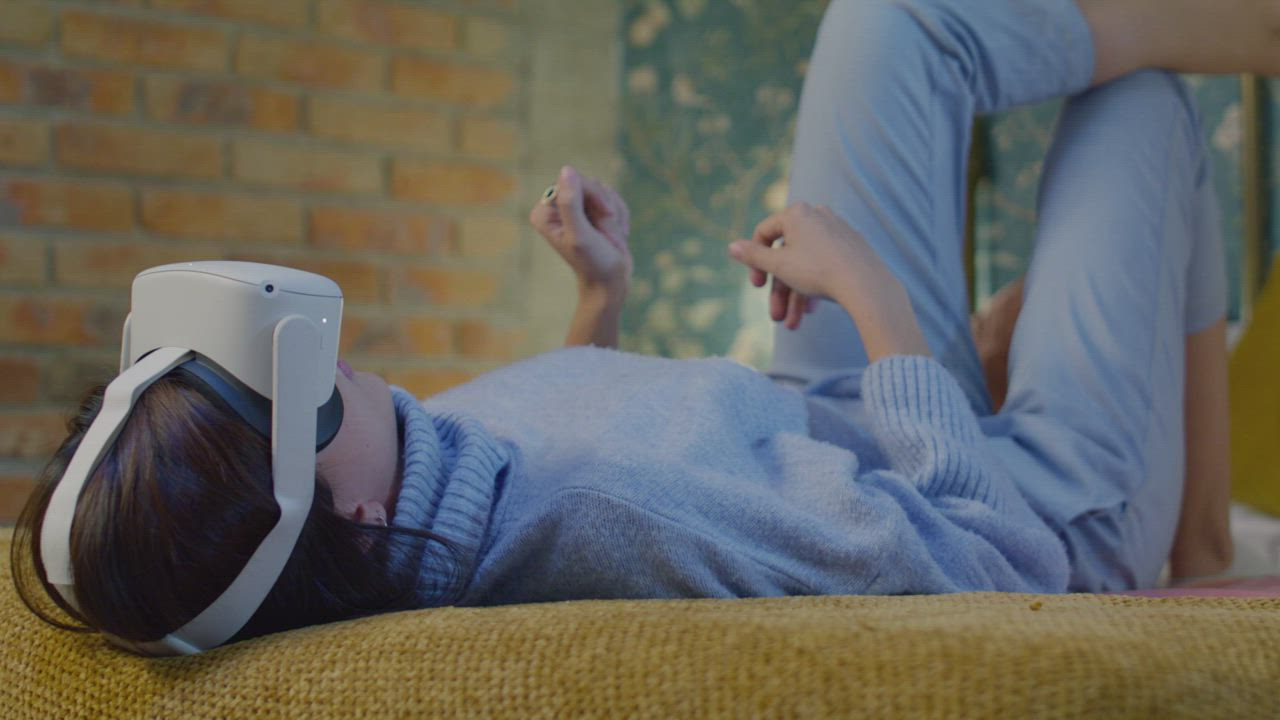 Woman lying down wearing virtual reality goggles - Free Stock Video