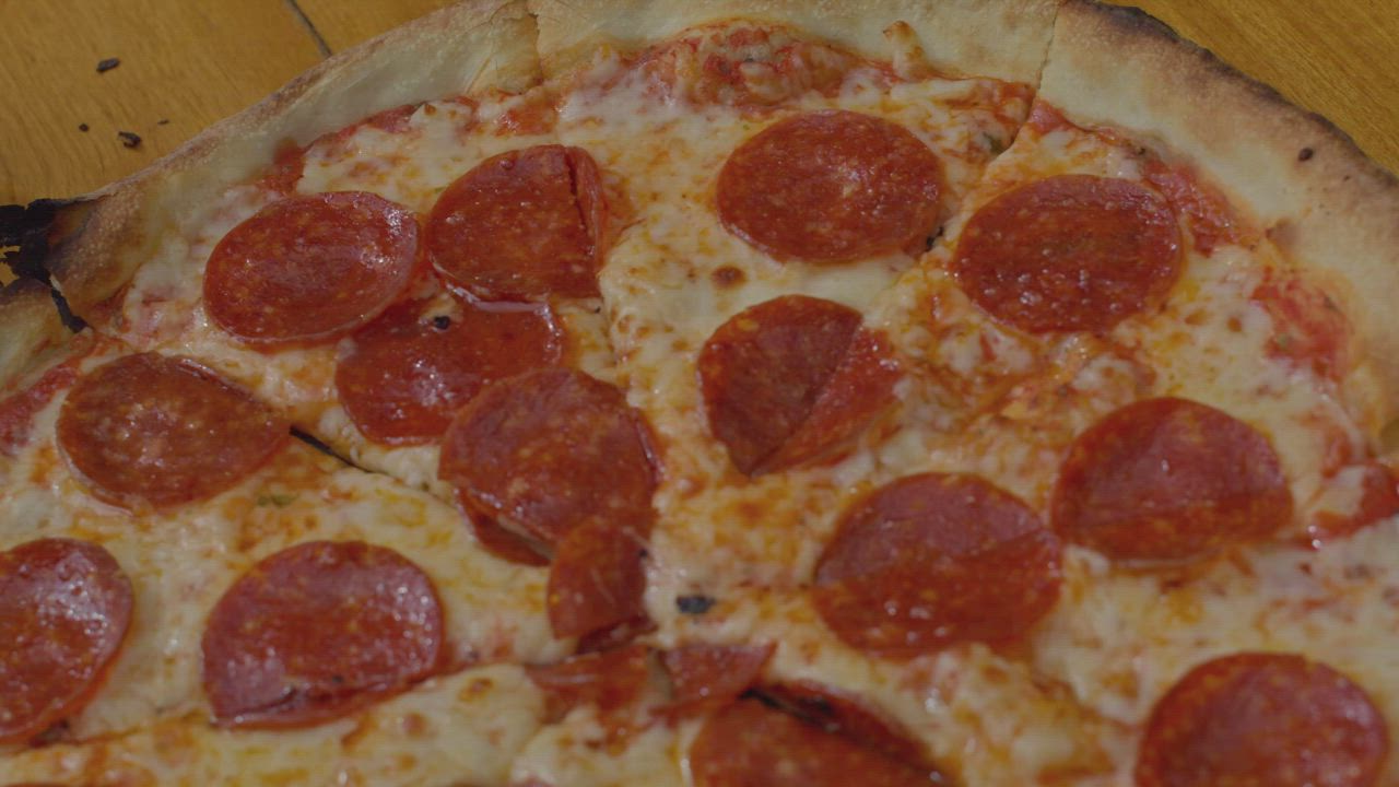 Close up shot of a pepperoni pizza on a table - Free Stock Video
