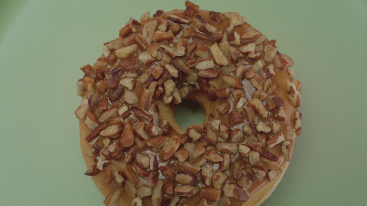 Donut with nut rotating on a pastel green background - Free Stock Video