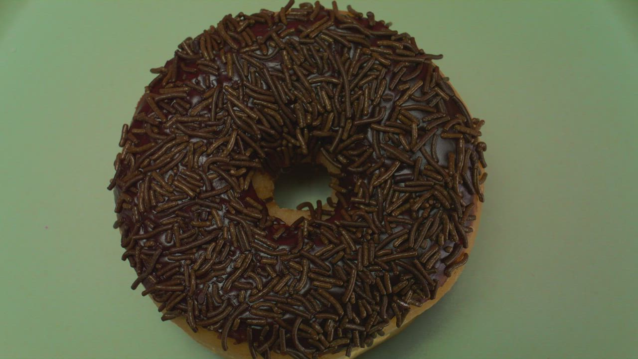 Close shot of a rotating chocolate donut - Free Stock Video