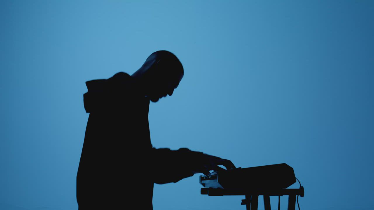 Shadow of a keyboardist playing on a blue background - Free Stock Video