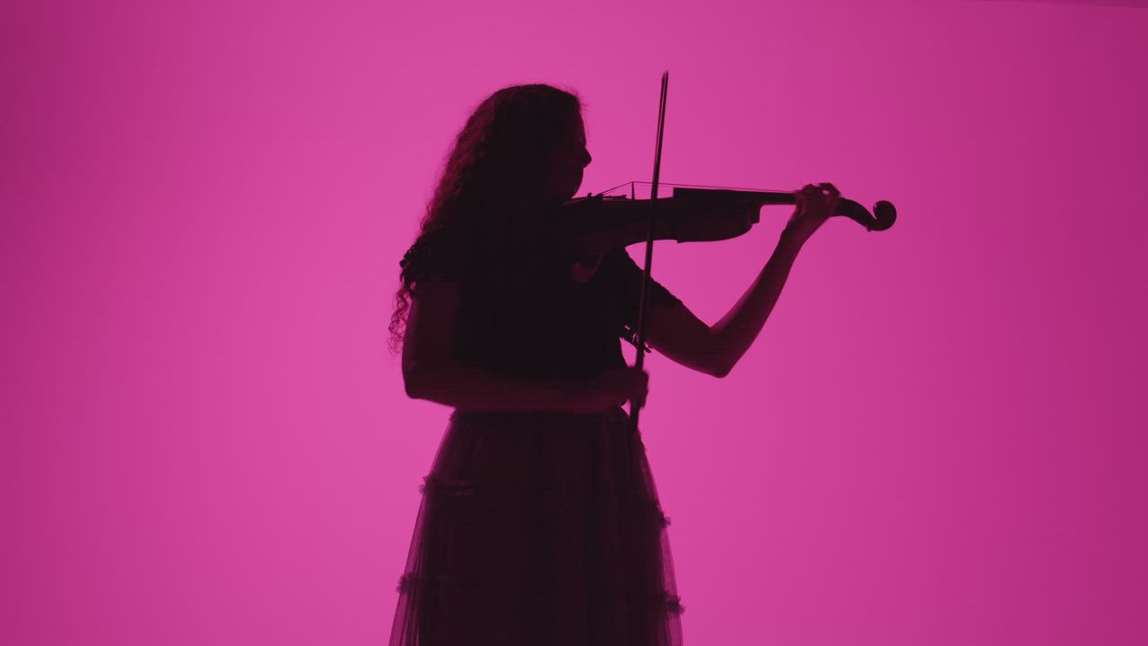 Shadow of a violinist playing on a pink background - Free Stock Video