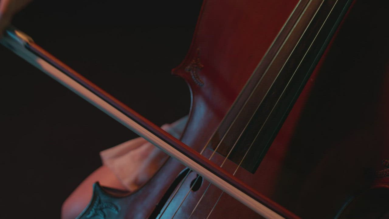 Close shot of a woman playing the cello in the dark - Free Stock Video