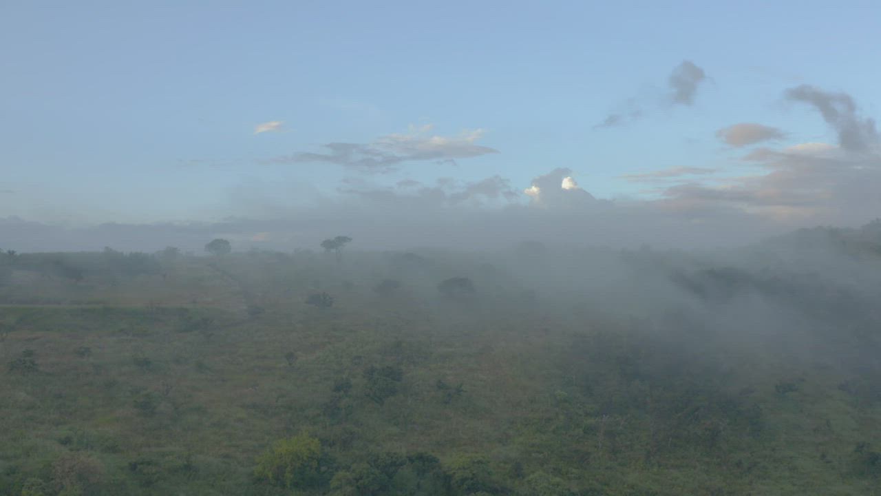 Flying over a hill covered in a cloud of mist - Free Stock Video