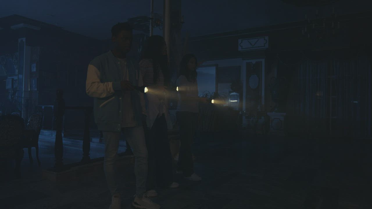 Three young people exploring a haunted house at night - Free Stock Video