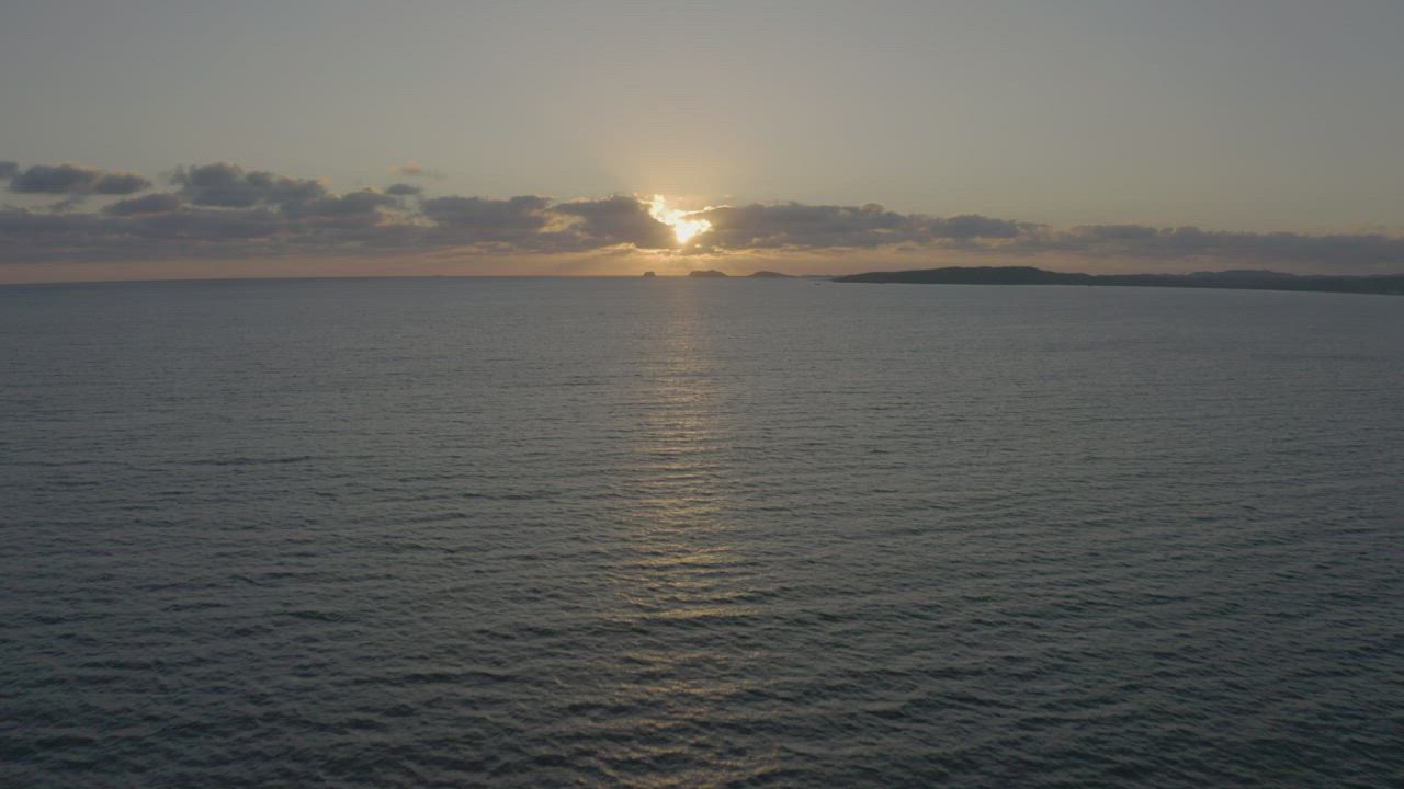 Aerial tour backwards over the sea at sunset - Free Stock Video