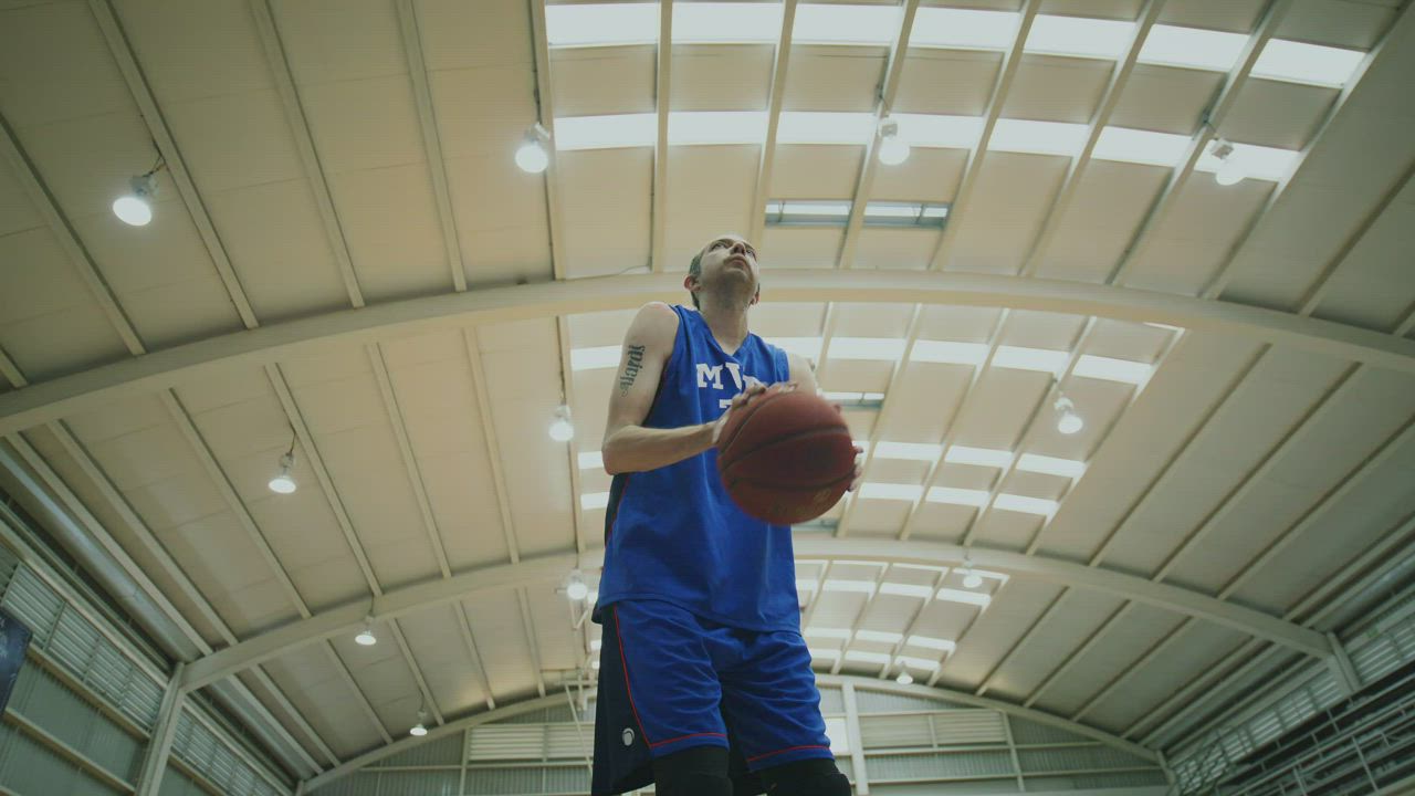 Basketball player training shots on a covered court - Free Stock Video